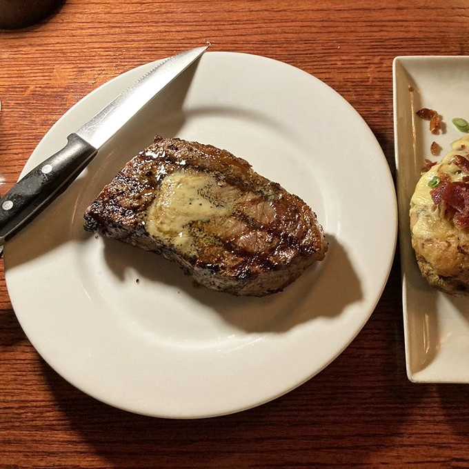Behold the steak that launched a thousand road trips. That melting pat of butter is performing a slow dance of deliciousness on perfectly seared beef.