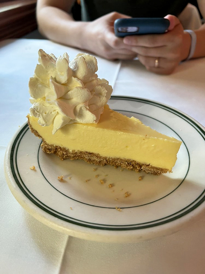 The key lime pie arrives like Florida sunshine on a plate&mdash;pale yellow custard, graham cracker foundation, and a cloud of whipped cream.
