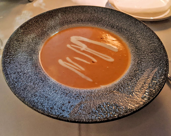 The legendary lobster bisque arrives like a coral-colored poem in a bowl, with cream swirls that deserve their own Instagram account.