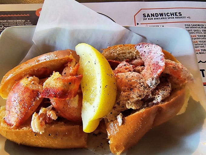 Lobster roll perfection: chunks of sweet meat nestled in a buttery split-top bun with a lemon wedge standing by for that essential citrus kiss.