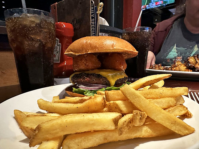 This isn't just a burger—it's architecture. Stacked high with melty cheese and nestled beside golden fries that demand equal attention.