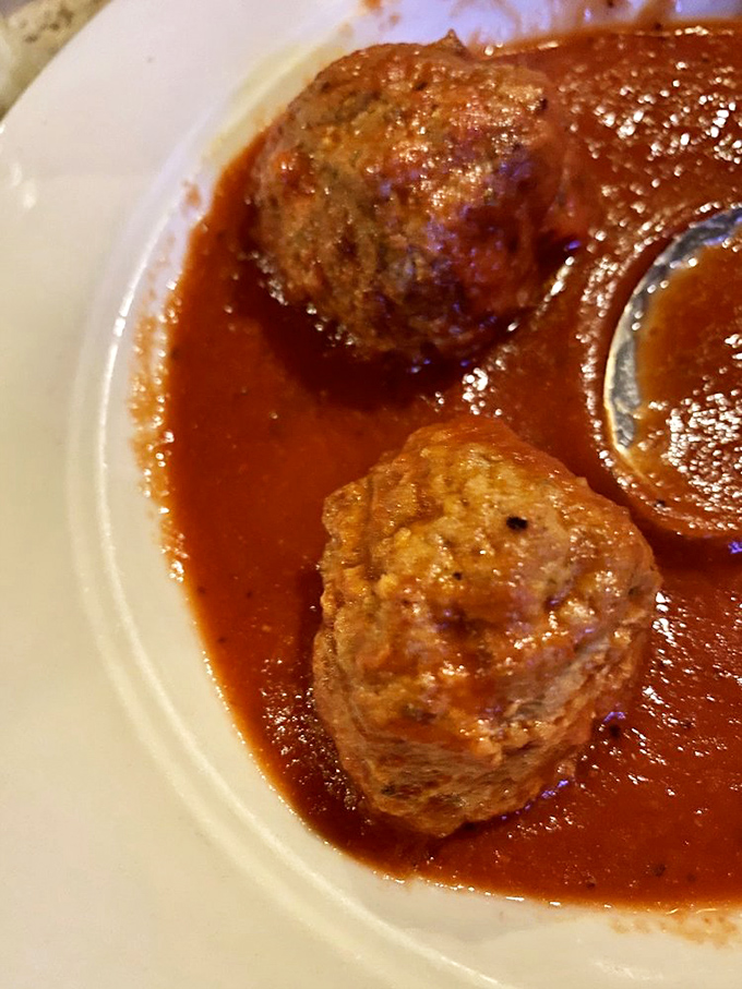 These meatballs aren't just food; they're time machines to Sunday dinners past, swimming gloriously in rich, vibrant house red sauce.