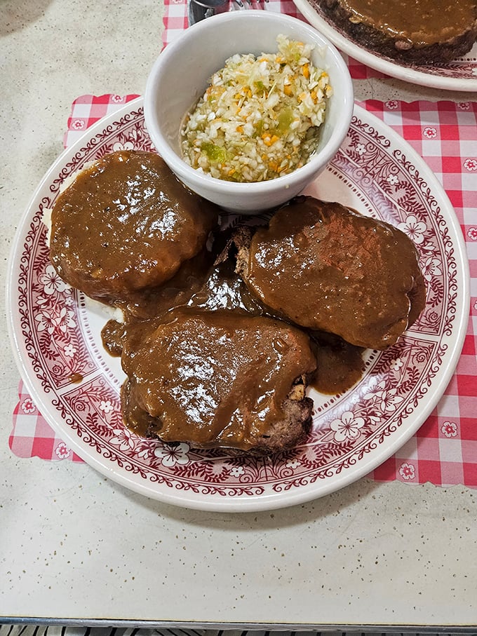 Behold the star attraction: meatloaf that would make your grandmother both jealous and proud, bathed in gravy that deserves its own fan club.