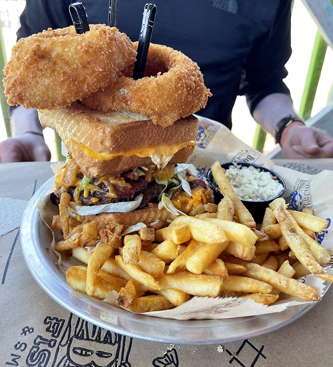 Skyscraper architecture meets comfort food engineering. This towering masterpiece with its onion ring crown demands both respect and extra napkins.