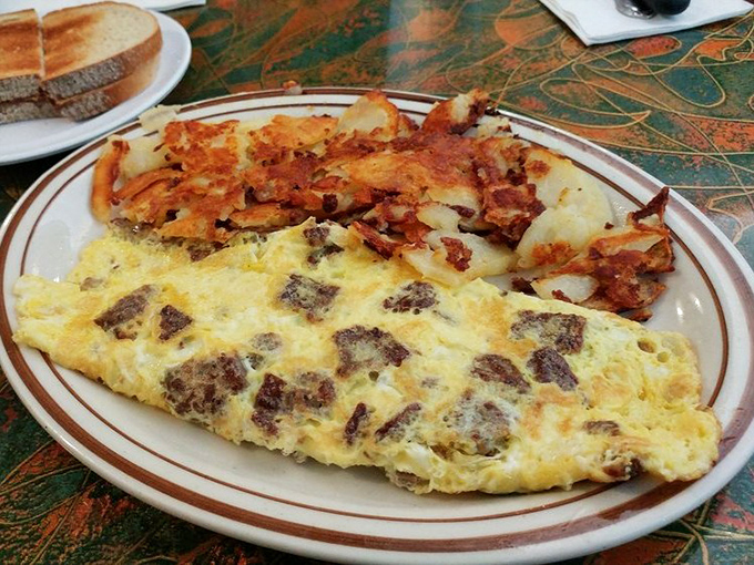 Behold the star attraction: a perfectly executed omelet alongside crispy home fries. This is breakfast architecture at its finest.