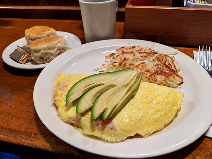 This isn't just an omelet; it's a perfectly folded yellow canvas showcasing the art of breakfast, with avocado slices adding that California touch.