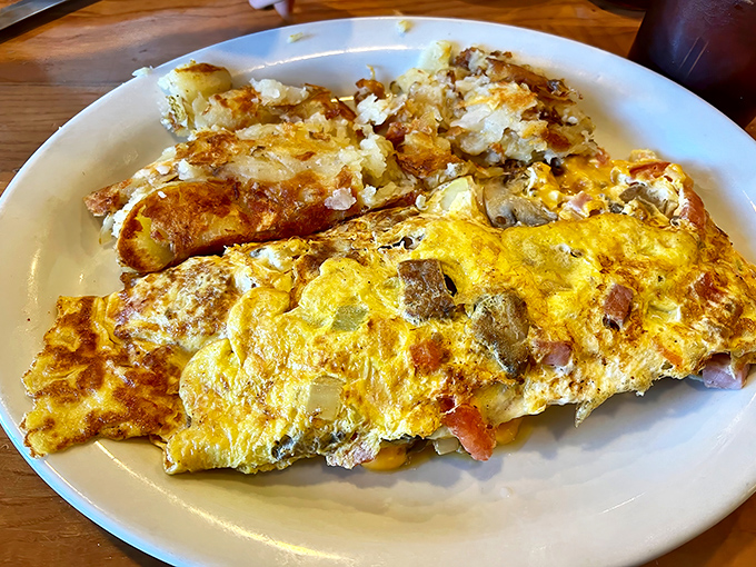 This isn't just an omelet&mdash;it's a golden canvas of perfectly cooked eggs cradling a medley of fillings. The home fries look like they're auditioning for a starring role.