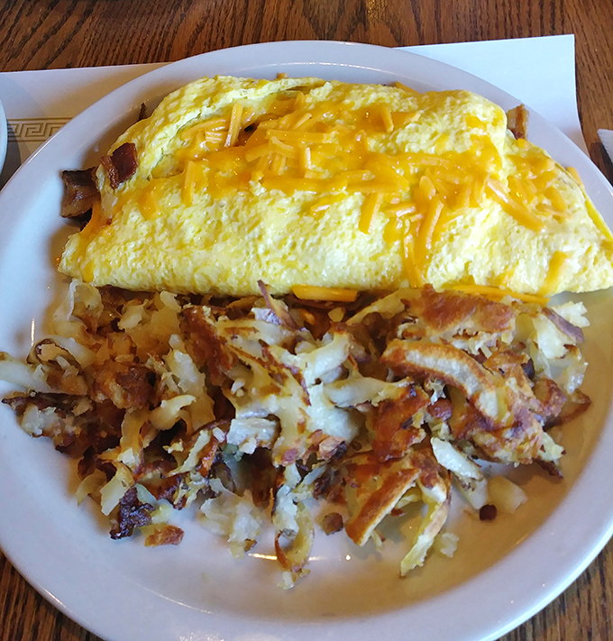 Behold the cheese omelet in its golden glory, perfectly paired with hash browns crispy enough to make a potato proud.