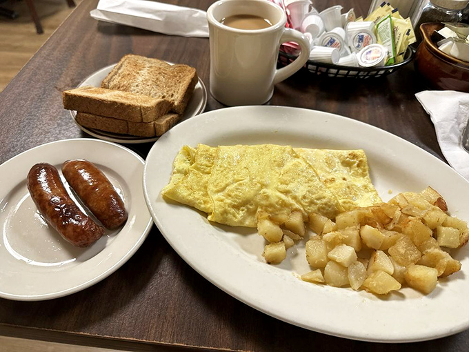 Breakfast geometry at its finest: a perfectly folded omelet, golden home fries, and sausages that snap with each bite.