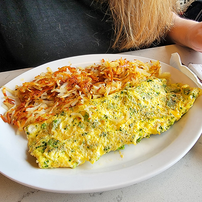 This omelet performs the ultimate magic trick: perfectly containing its fillings while maintaining that coveted fluffiness, with hash browns that crackle with each bite.
