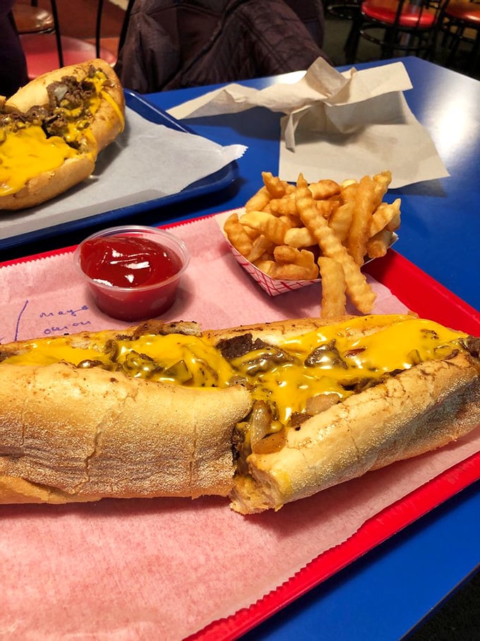Cheese cascading over thinly sliced steak like a golden waterfall, with crinkle-cut fries standing by for backup. This is sandwich architecture at its finest.