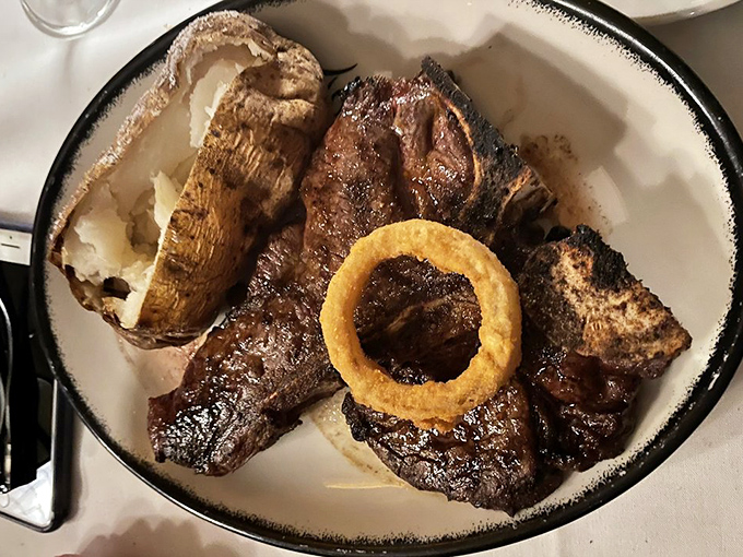 Behold the star of the show: a porterhouse that makes vegetarians question their life choices, accompanied by a perfectly golden onion ring.