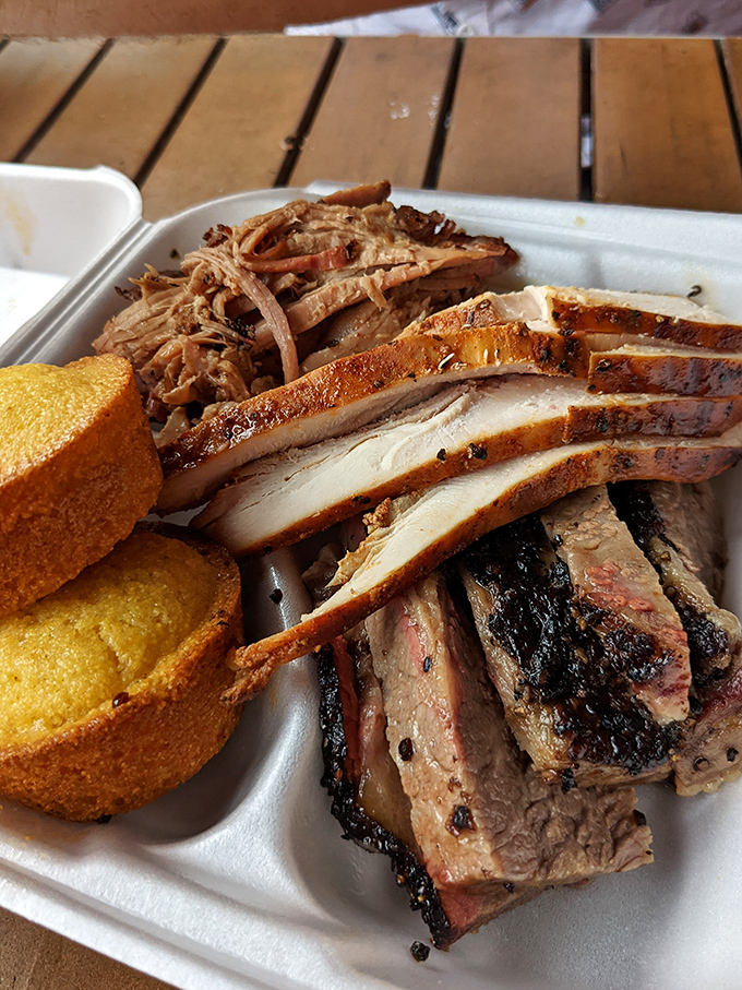 Behold the holy trinity of BBQ: pulled pork, brisket, and chicken, accompanied by golden cornbread that's worth the trip alone.