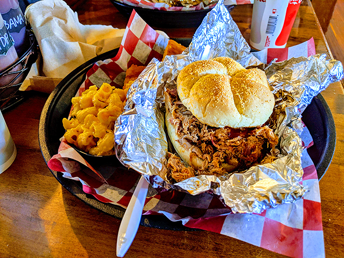 This pulled pork sandwich isn't messing around &ndash; tender strands of smoky meat cradled in a soft bun with mac and cheese standing guard.
