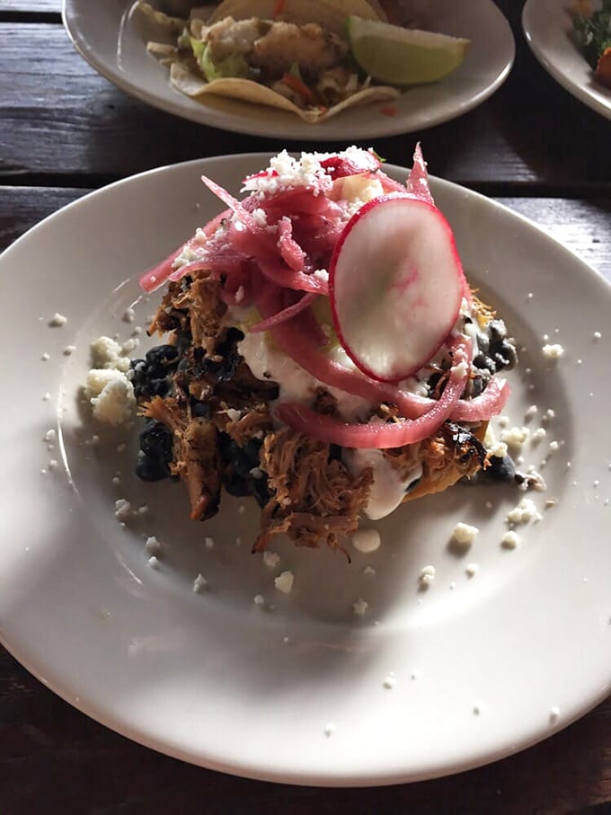 The infamous pulled pork tostada arrives like edible architecture – layers of slow-roasted meat, vibrant pickled onions, and cotija cheese create a perfect balance that makes taste buds stand and applaud.