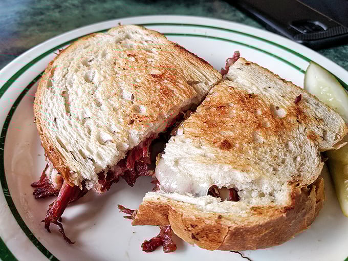 The legendary Reuben in all its glory&mdash;perfectly grilled rye bread giving way to tender corned beef. That pickle spear isn't just garnish; it's the palate cleanser before your next heavenly bite.