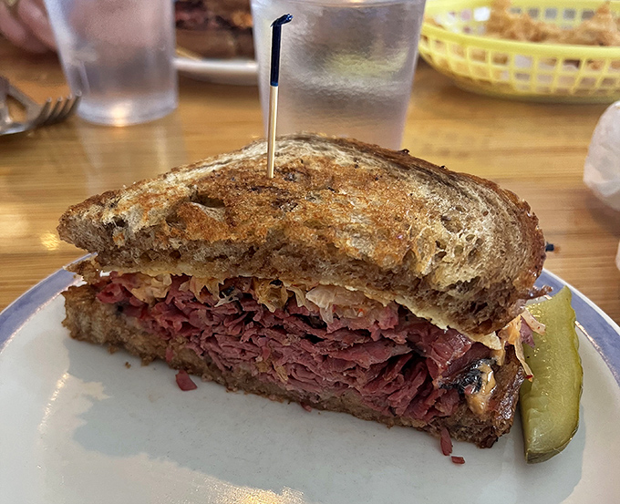 Behold the star of our show: layers of house pastrami stacked between perfectly grilled rye, with that pickle standing guard like a delicious sentinel.