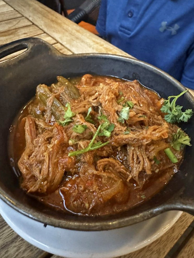 Ropa Vieja—"old clothes" by name, royal feast by nature. Tender shredded beef swimming in a tomato bath that demands to be sopped up.