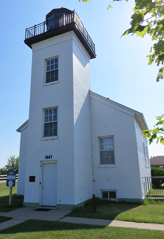 Sandpoint Lighthouse has guided mariners since 1867, standing as stoically as a Midwestern grandparent who's "seen it all" but keeps the light on anyway.