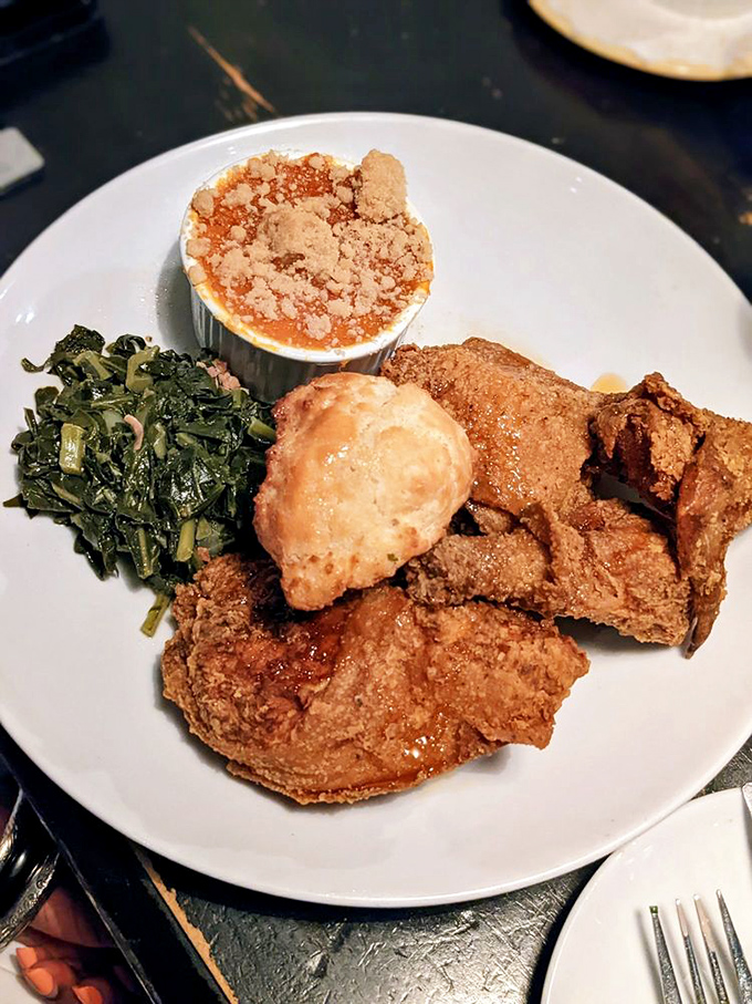 Golden-brown fried chicken, collard greens, and what appears to be sweet potato casserole&mdash;the holy trinity of Southern comfort on a pristine white plate.