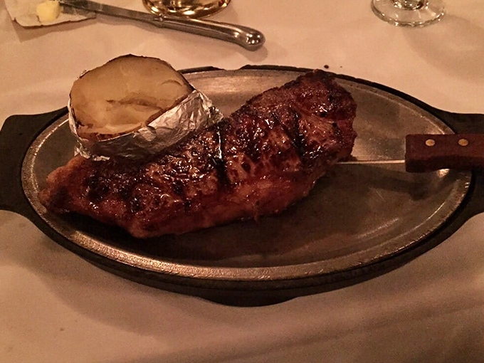 Behold the carnivore's dream! A perfectly seared steak alongside a baked potato wrapped in foil like it's wearing a tiny silver spacesuit.