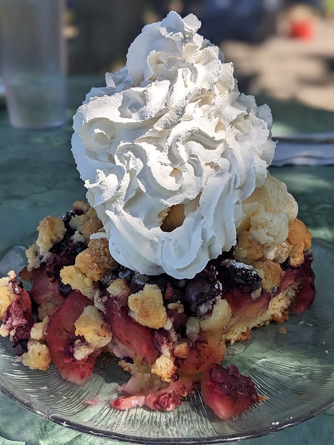Behold the star attraction: a berry-packed cobbler crowned with a cloud of whipped cream that makes grown adults contemplate licking the plate when nobody's watching.