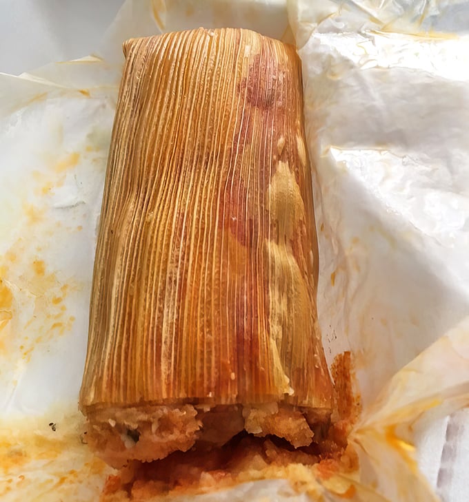Behold the star of the show: a perfectly steamed tamale unwrapped from its corn husk cocoon. The masa-to-filling ratio here is what dreams are made of.