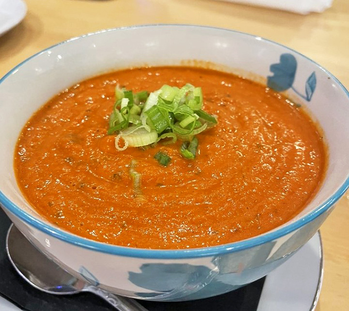 The famous tomato soup that launched a thousand real estate inquiries. That vibrant orange hue and fresh scallion garnish promise warmth in every spoonful.