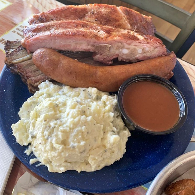 Meat trifecta that would make a rancher weep with joy. Ribs, sausage, and potato salad create the holy trinity of barbecue satisfaction on this blue plate special.