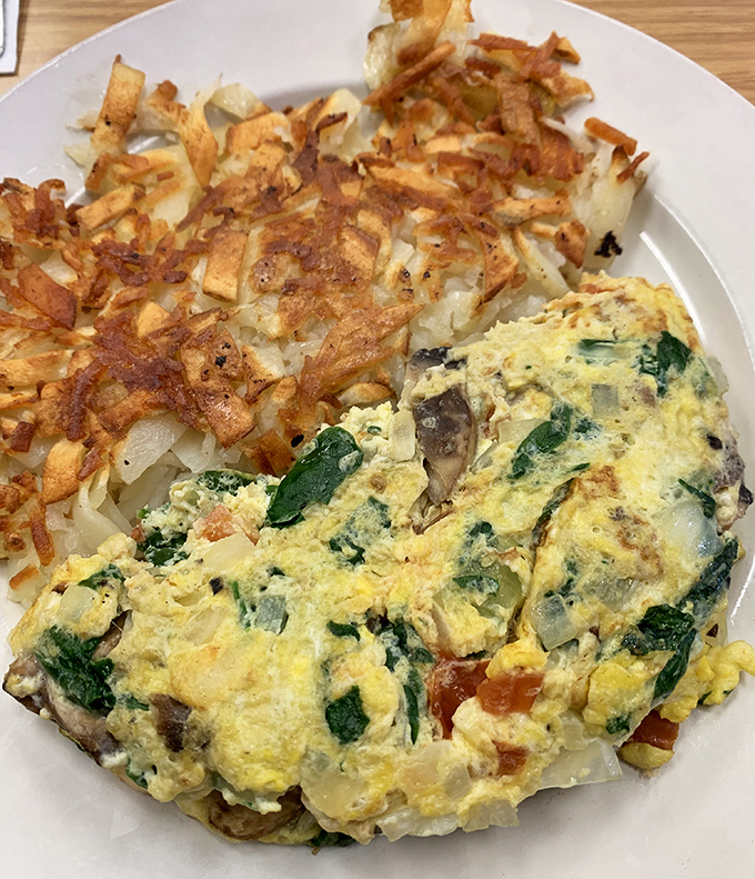 Behold the perfect marriage: a vegetable-packed omelet that makes you feel virtuous alongside hash browns that remind you life is meant to be enjoyed.