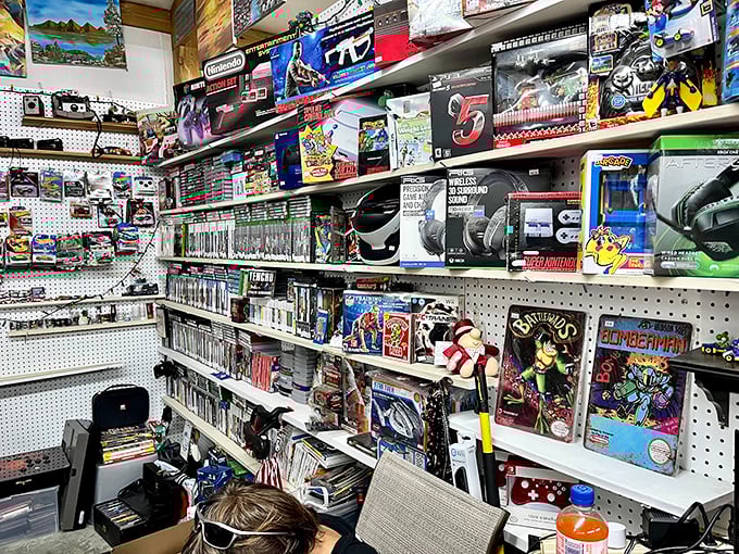 Gaming paradise where nostalgia comes with a price tag. Every shelf tells a story of late nights, forgotten passwords, and "just one more level."