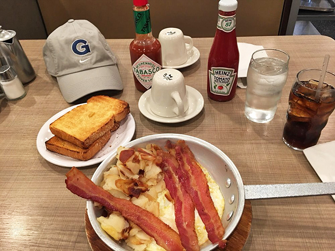Breakfast architecture at its finest&mdash;crispy hash browns supporting strips of bacon like delicious load-bearing walls. The Cubs cap suggests this is serious Chicago business.