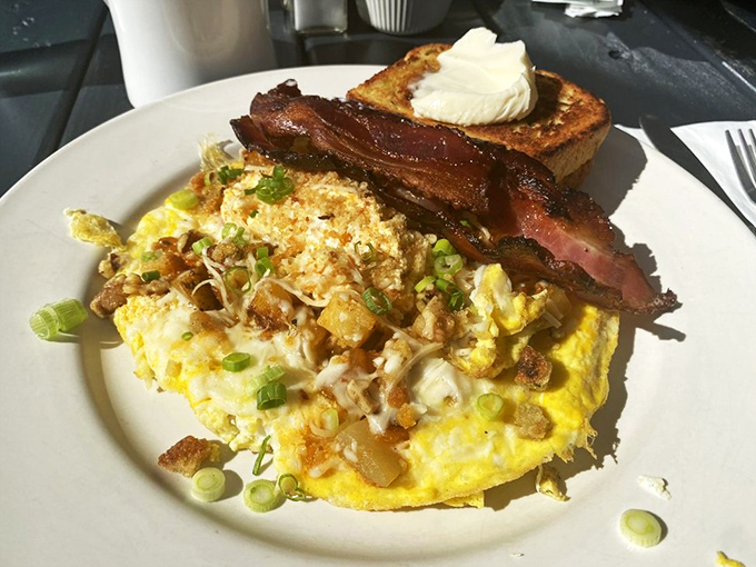 Breakfast nirvana achieved: a golden omelet bursting with fillings, perfectly crisped bacon, and toast that didn't forget its morning butter bath.