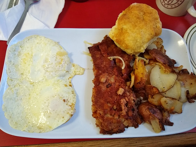 Breakfast perfection on a plate: golden-fried country steak, home fries with crispy edges, eggs with just-right yolks, and a biscuit that demands attention.