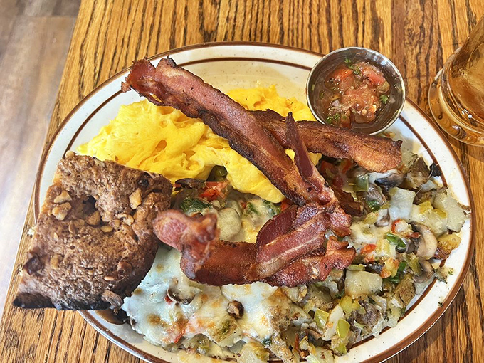Breakfast nirvana on a plate: golden scrambled eggs, crispy bacon, and home fries that could make a potato farmer weep with joy.