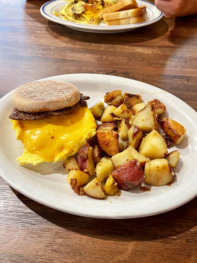 Breakfast sandwich perfection: melty cheese cascading over a perfectly cooked egg, with home fries that achieve the golden-brown ideal every potato aspires to.