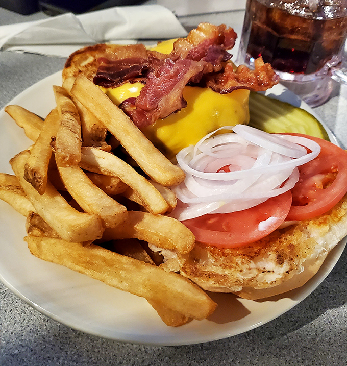 This isn't just a cheeseburger; it's architecture. A golden-toasted bun foundation supporting the perfect cheese-bacon-tomato skyline.