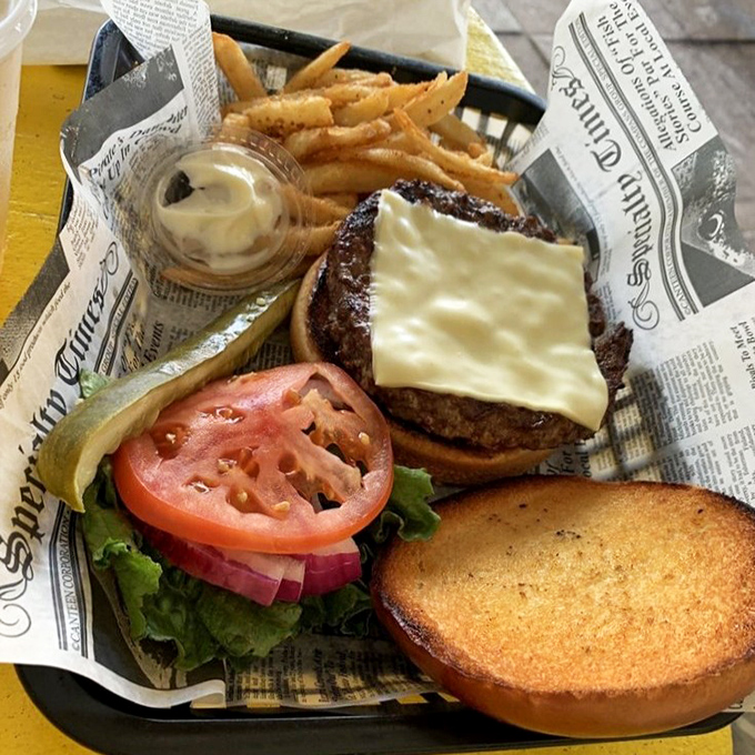 The legendary cheeseburger arrives like a humble hero, newspaper-wrapped and unassuming, yet ready to conquer hunger with melty, beefy perfection.