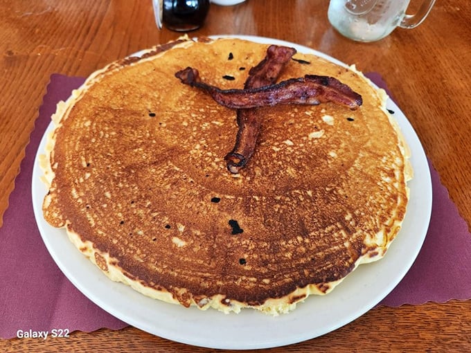 That's not a pancake, that's an edible frisbee! Golden, fluffy, and topped with a bacon smile that knows exactly how good it is.