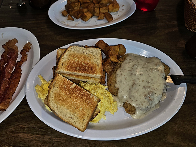 Country fried steak smothered in peppery gravy alongside golden home fries and toast &ndash; the breakfast equivalent of a warm hug from your favorite aunt.