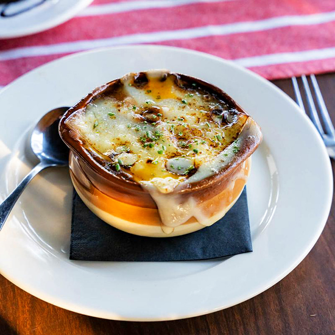 Behold the crown jewel: French onion soup with a cheese pull that deserves its own slow-motion sequence. Spoons ready for this bubbling masterpiece!