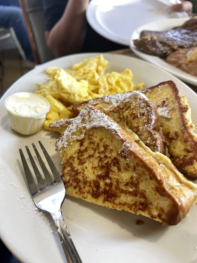 Golden-edged French toast dusted with powdered sugar alongside fluffy scrambled eggs&mdash;breakfast perfection that makes you want to high-five the cook.