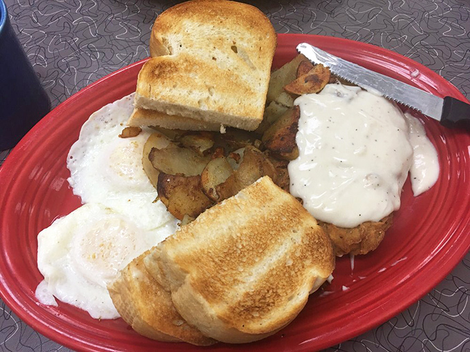 Breakfast nirvana on a red plate: perfectly fried eggs, golden home fries, and toast that's achieved that mythical balance between crisp and soft. The breakfast trifecta.