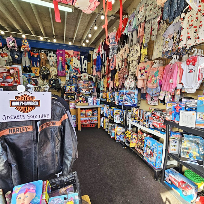 Retail therapy on steroids! This packed booth showcases the delightful chaos of swap meet shopping—Harley jackets hanging alongside children's toys and collectibles.