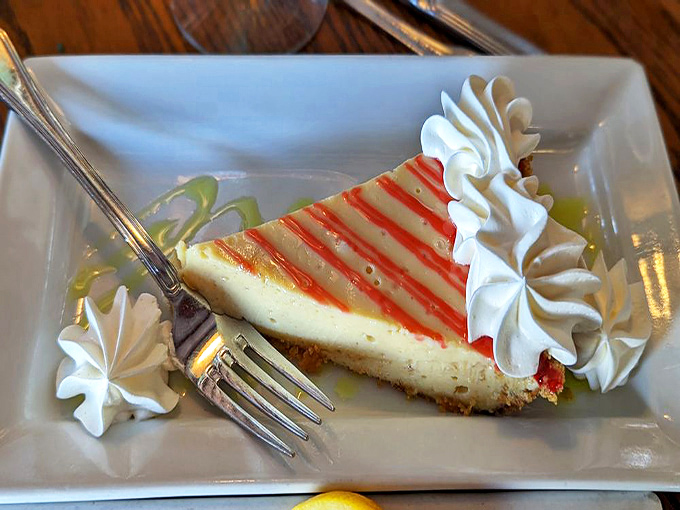 Key lime pie perfection: the ideal balance of sweet and tart, topped with artistic raspberry drizzle and whipped cream rosettes.