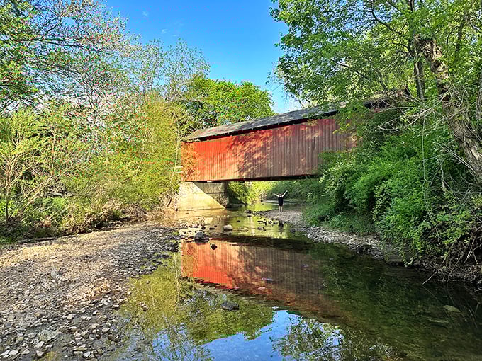 The bridge's reflection doubles the visual delight, creating a perfect mirror image in Sandy Creek's calm waters on a clear day.