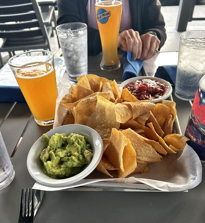 Tortilla chips form a golden mountain around fresh guacamole and salsa, while Blue Moon beers stand by, ready for their supporting role.