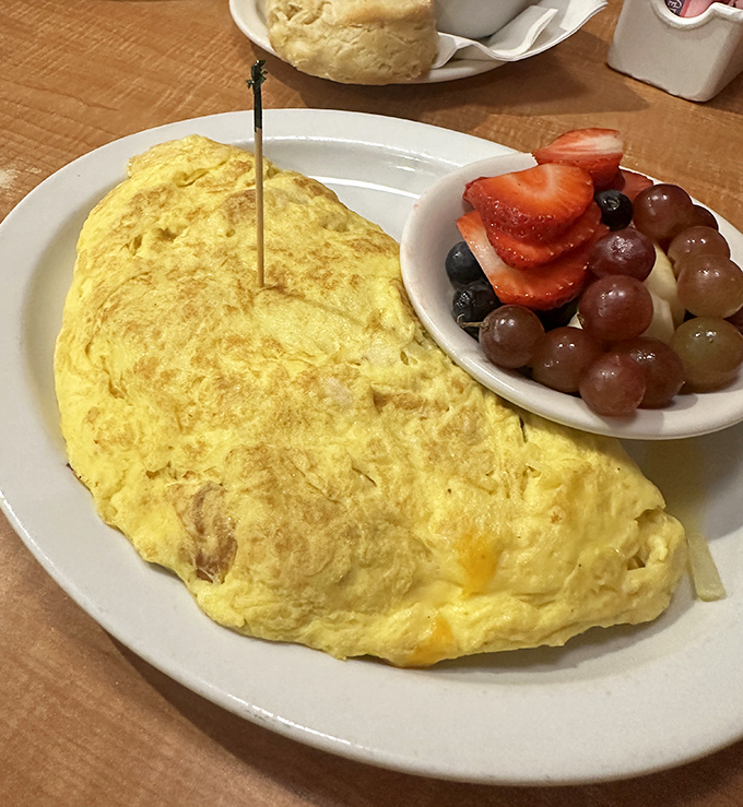 The golden-hued omelet arrives like a sunrise on your plate, accompanied by a fruit cup that's practically posing for its Instagram moment.