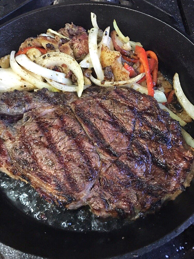 A perfectly seared steak sizzles alongside caramelized onions and peppers&mdash;proof that German cuisine isn't just about sausages and sauerkraut.