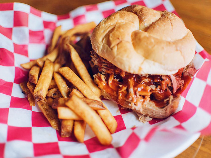 This pulled pork sandwich isn't just a meal; it's an architectural marvel of tender meat and sauce that somehow maintains structural integrity until the last bite.
